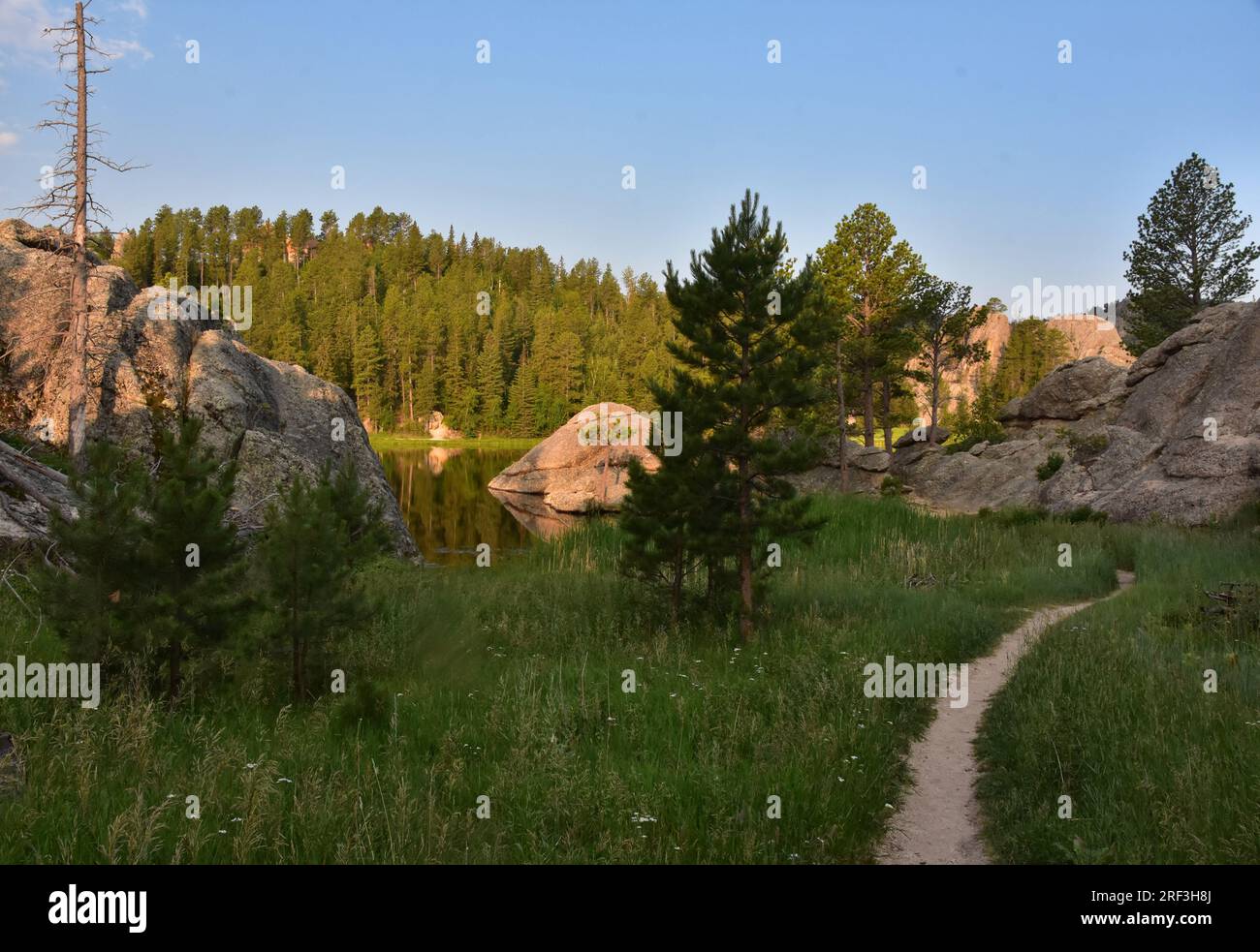 Dirt hiking trail with large granite rocks going around a lake in South ...