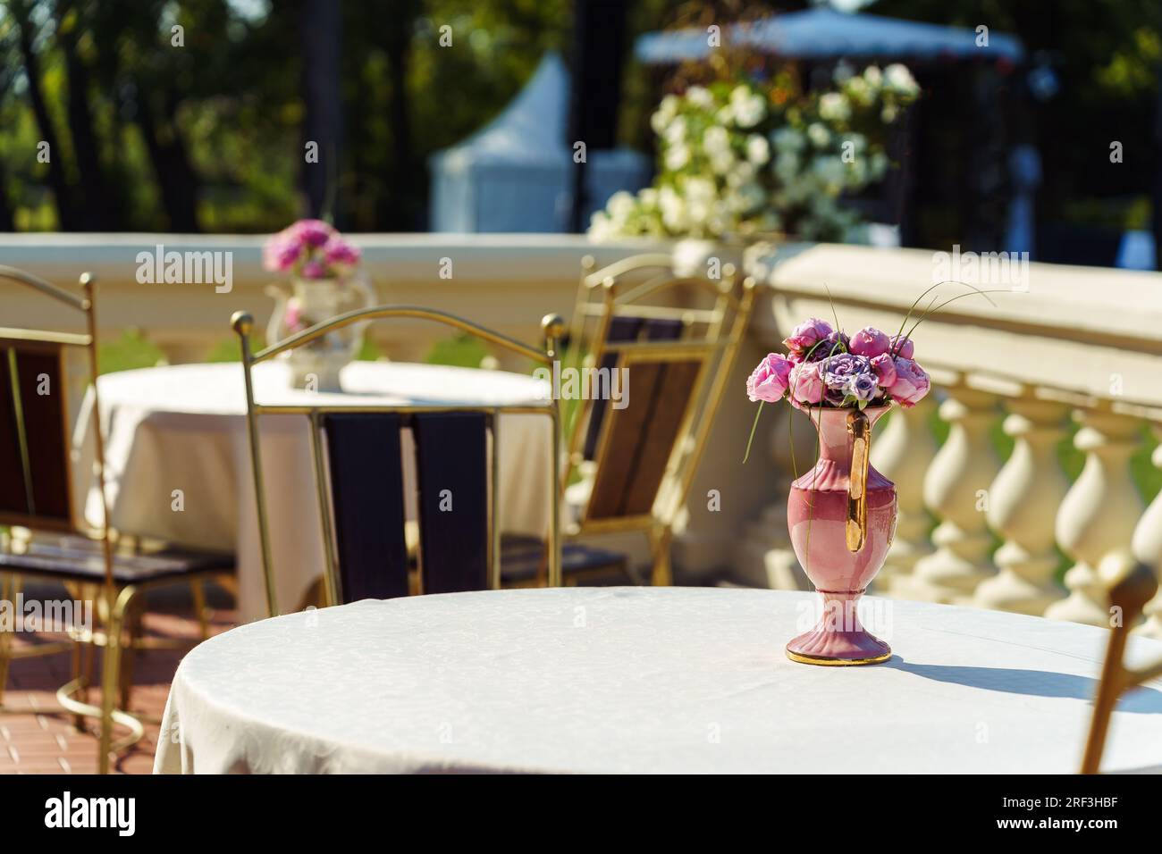 The tables are decorated with vases of fresh flowers on the outdoor ...