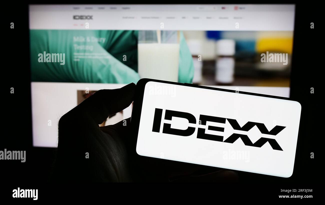 Person holding mobile phone with logo of US veterinary company IDEXX ...