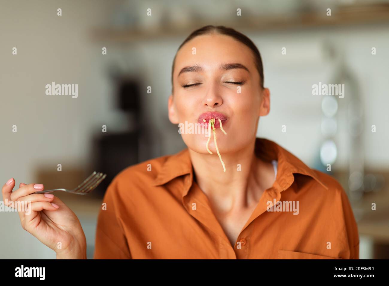Funny young caucasian lady tasting homemade spaghetti, enjoying pasta ...