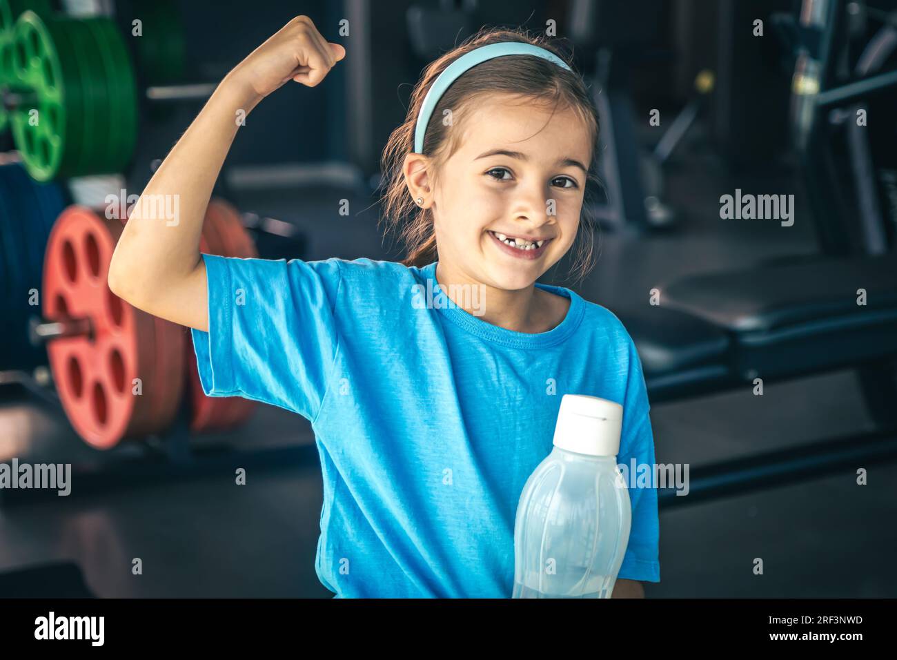 Charming little girl is shows her biceps, working out at gym Stock ...
