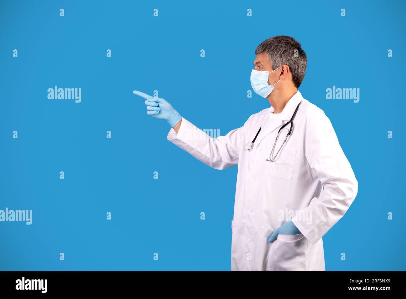 Doctor man pointing fingers aside at space over blue background Stock ...