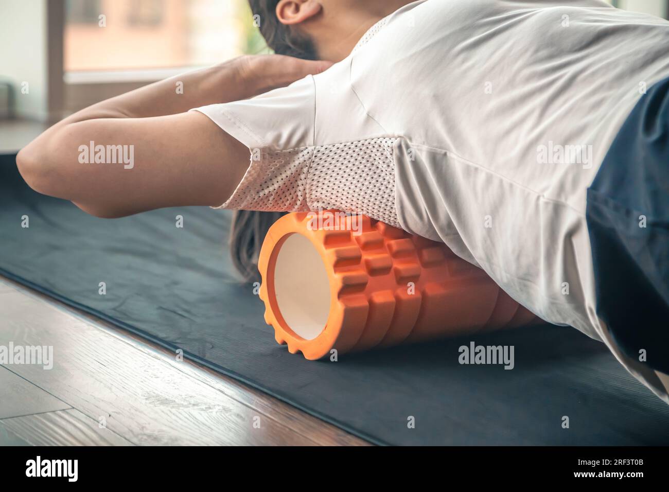 A woman uses a foam roller massager for stretching muscles and back ...