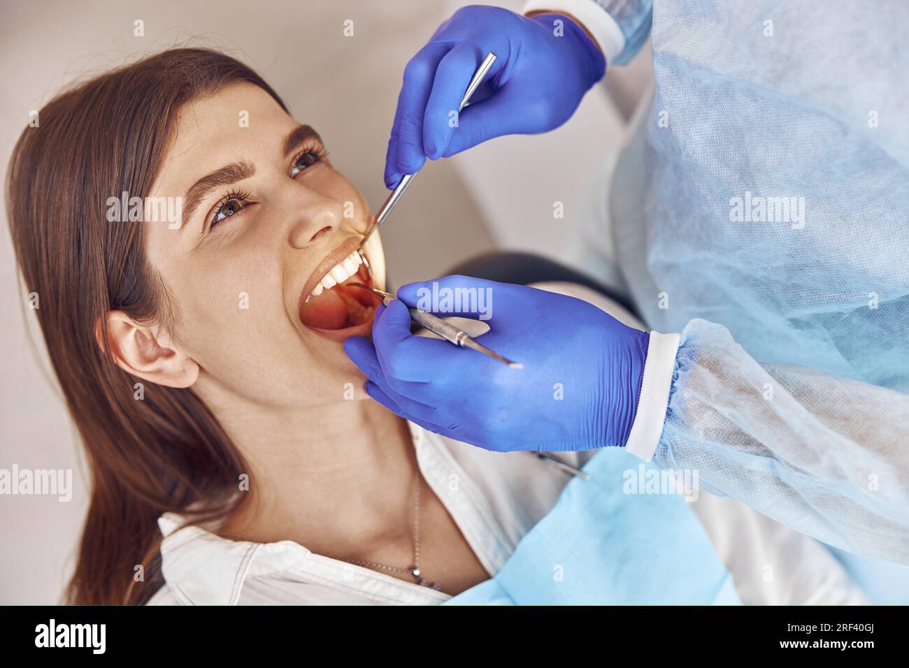 Professional doctor is doing tooth surgery to happy caucasian woman in ...