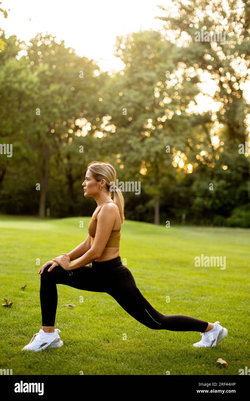 Pretty young woman doing stretching in the park Stock Photo - Alamy