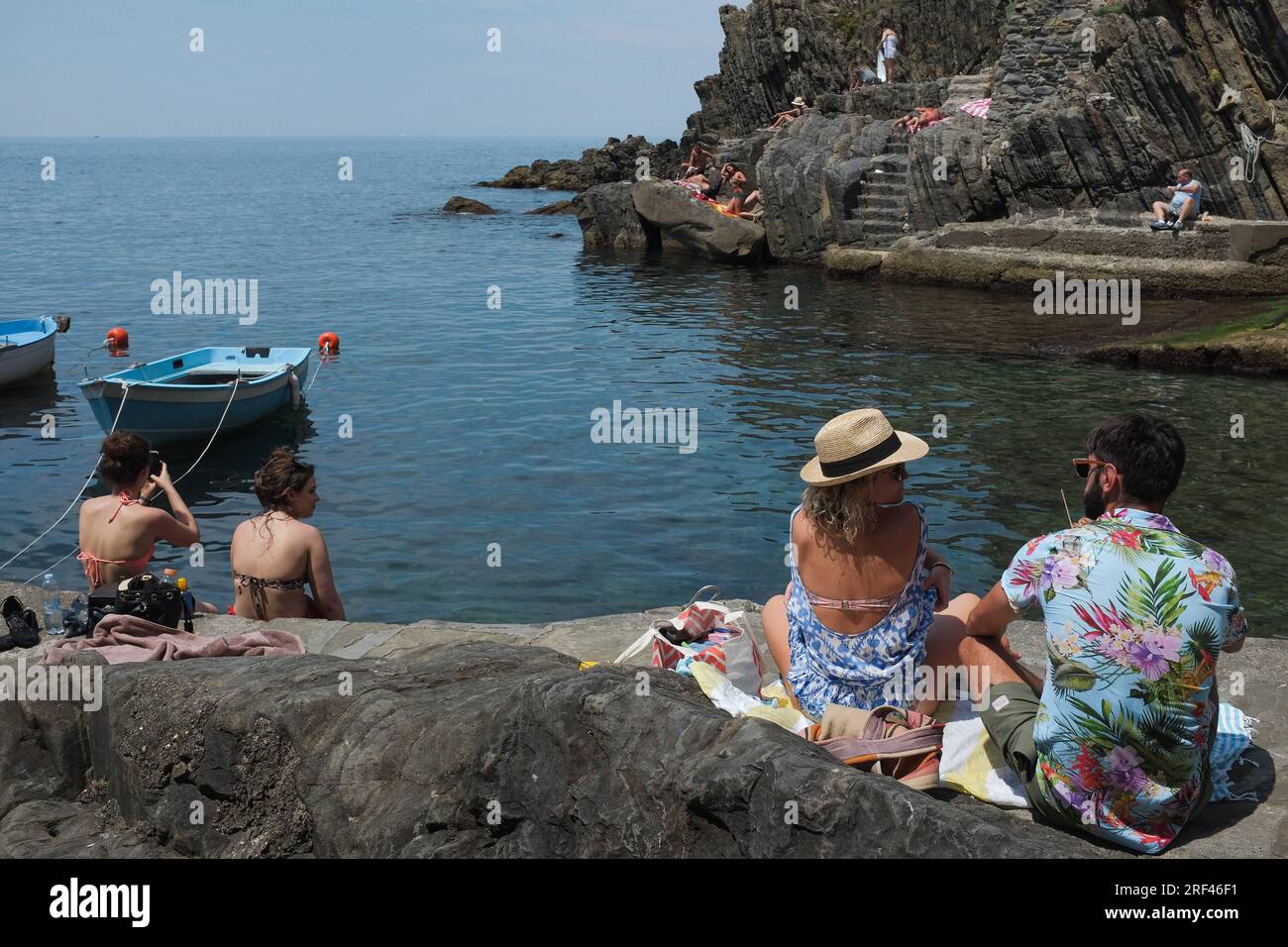 Cinque Terre, Italy - tourists in swimsuits sunbathe at Riomaggiore ...