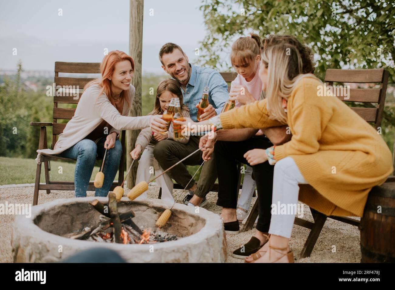 Group of friends having good time and baking corns in the house ...