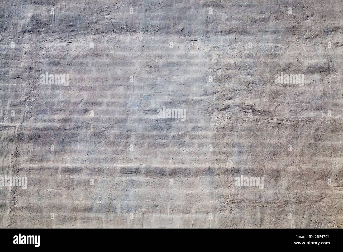 old plastered brick wall made of a large number of building materials ...