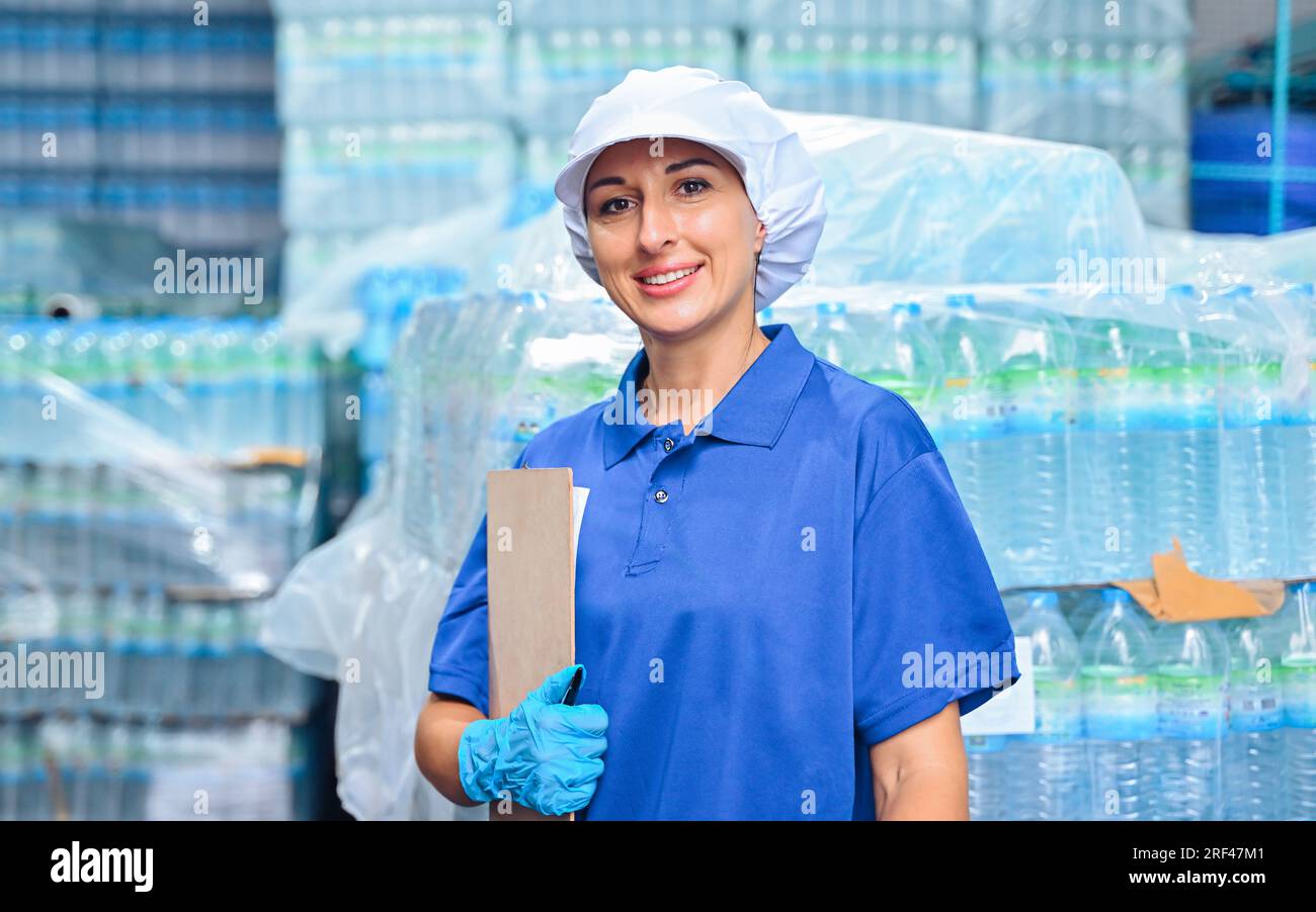 Bottling factory worker inspecting quality of water bottles before ...