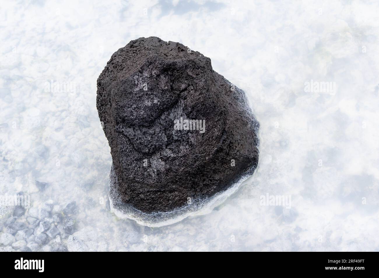 Black rock in milky white waters of Icelandic thermal nature baths near ...