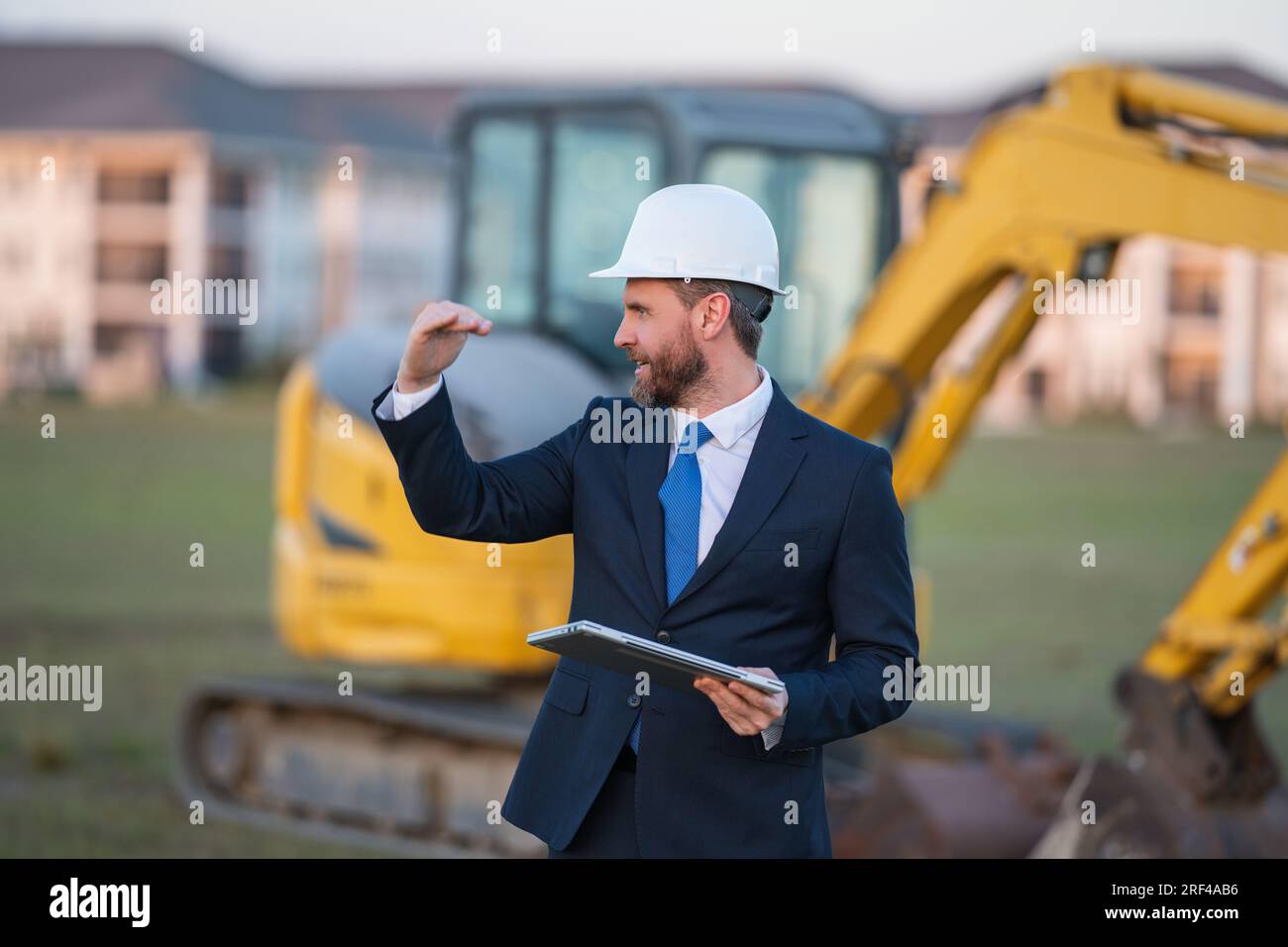 Architect at a construction site. Architect man in helmet and suit at ...