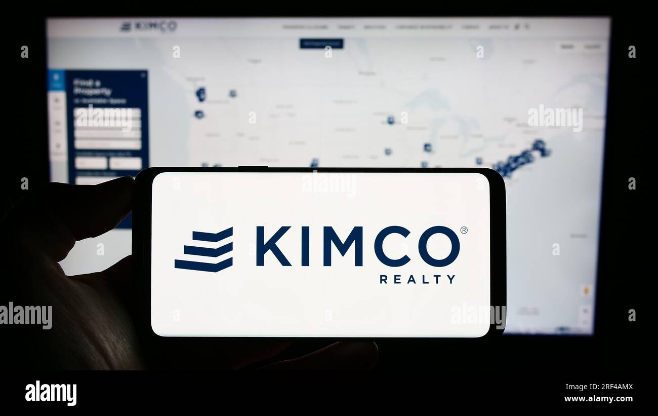 Person holding cellphone with logo of US real estate company Kimco ...