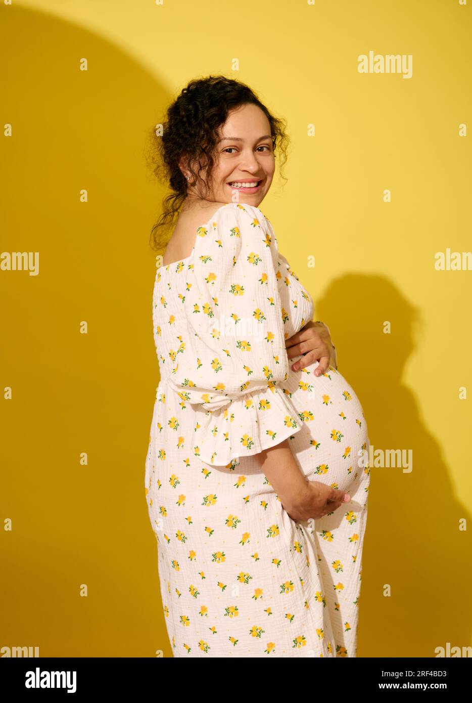 Curly multiethnic pregnant woman expecting a baby, smiling broadly ...