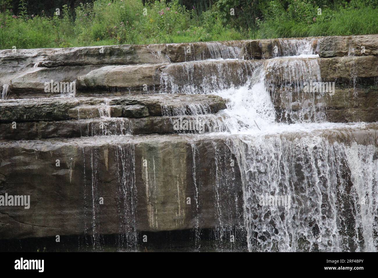 Water spills over the top of a small waterfall Stock Photo - Alamy