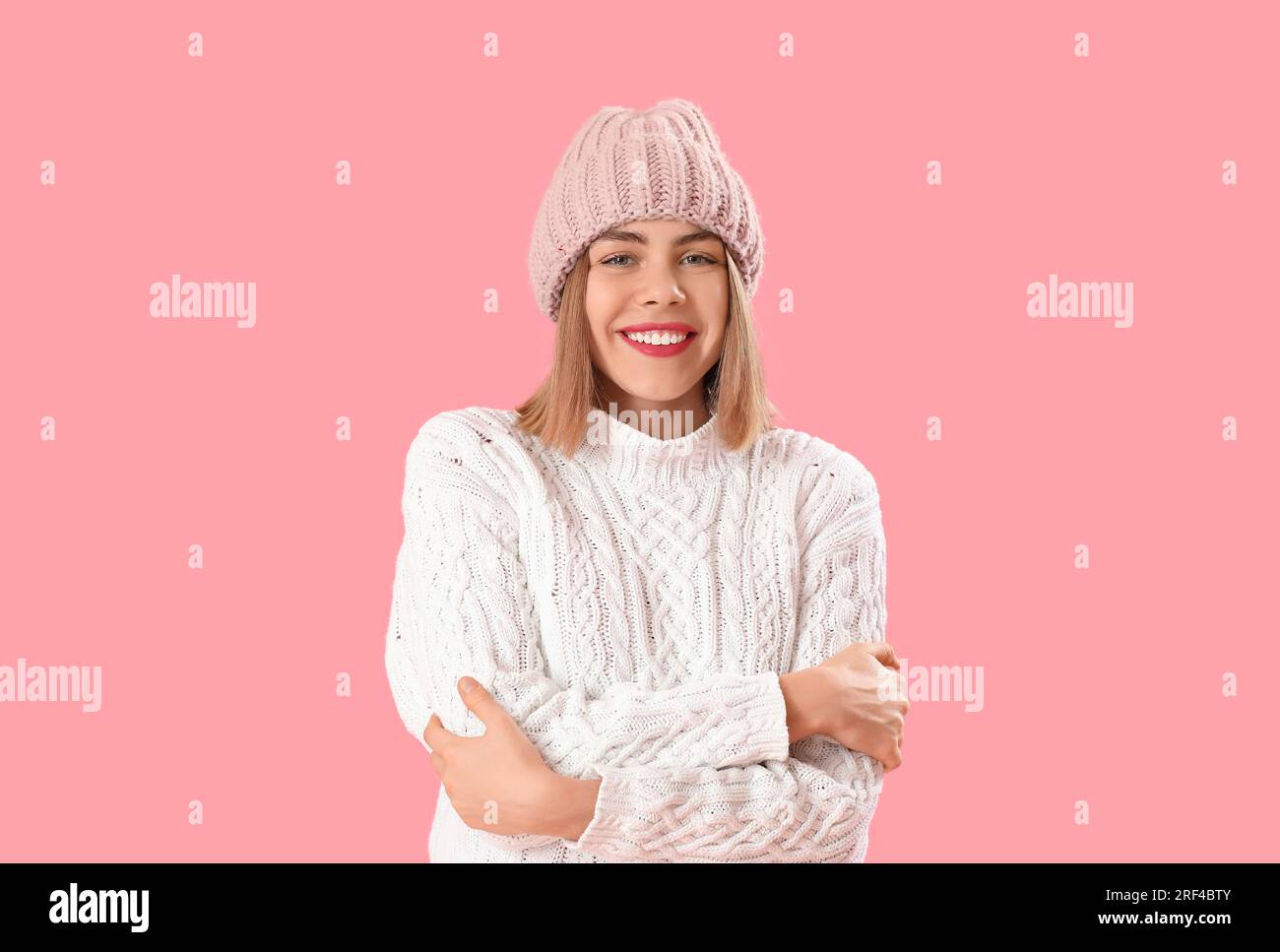Frozen young woman in winter clothes on pink background Stock Photo - Alamy