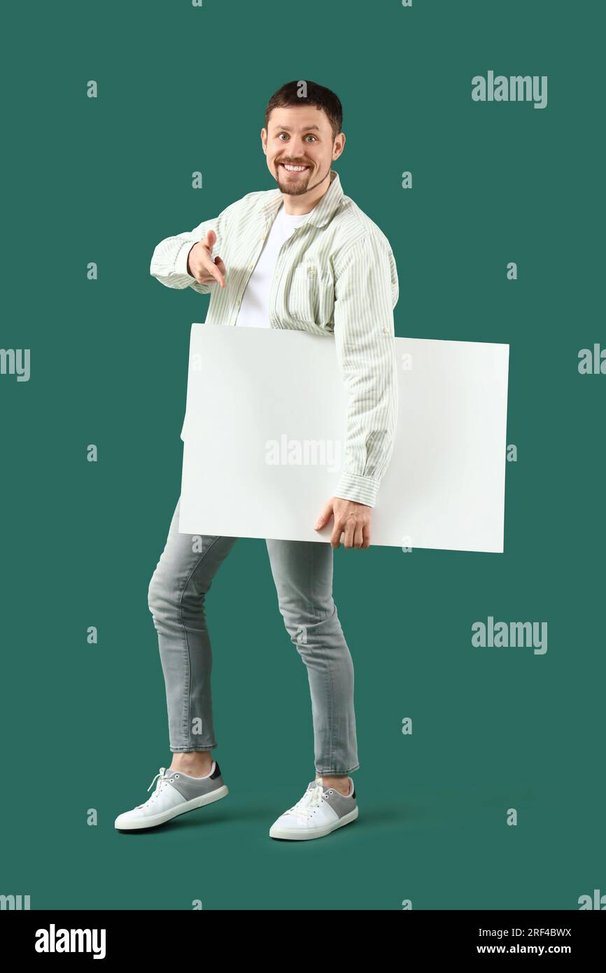 Handsome man pointing at big blank poster on green background Stock ...