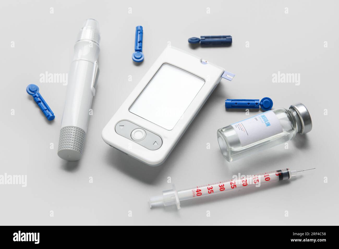 Glucometer with lancet pen, insulin and syringe on grey background ...