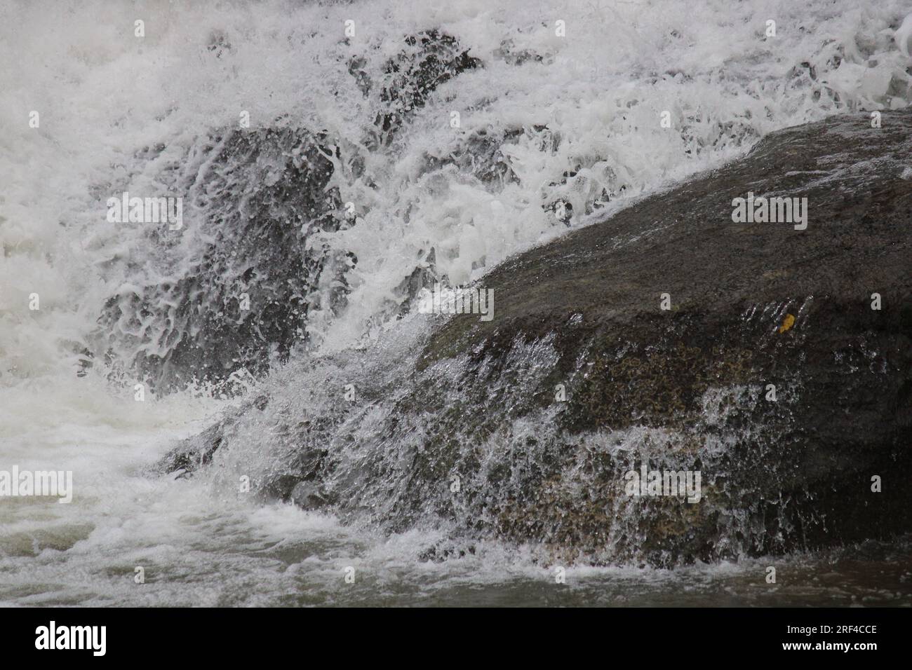 Water from a waterfall rushes around a rock Stock Photo - Alamy