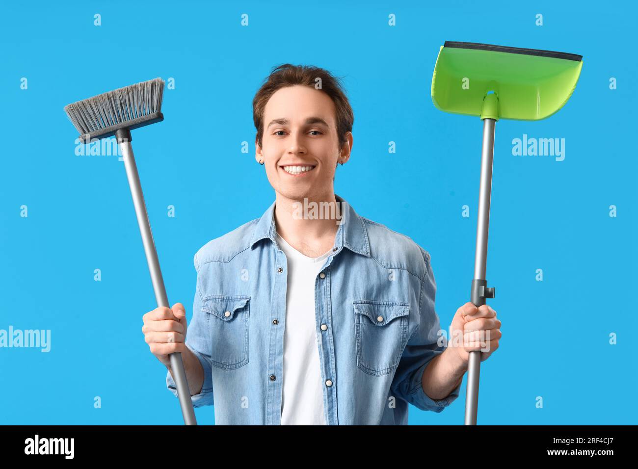 Young man with broom and dustpan on blue background Stock Photo - Alamy