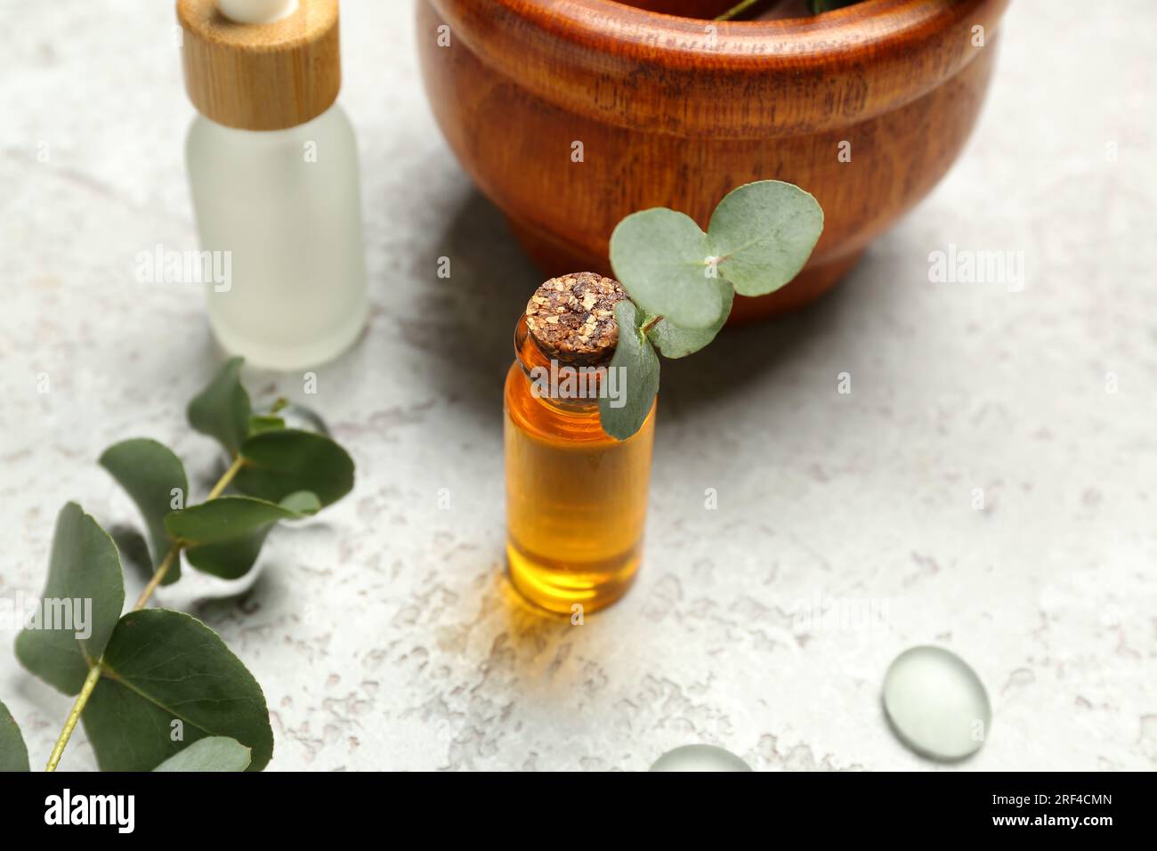Cosmetic oil bottles with wooden mortar and pestle and eucalyptus ...