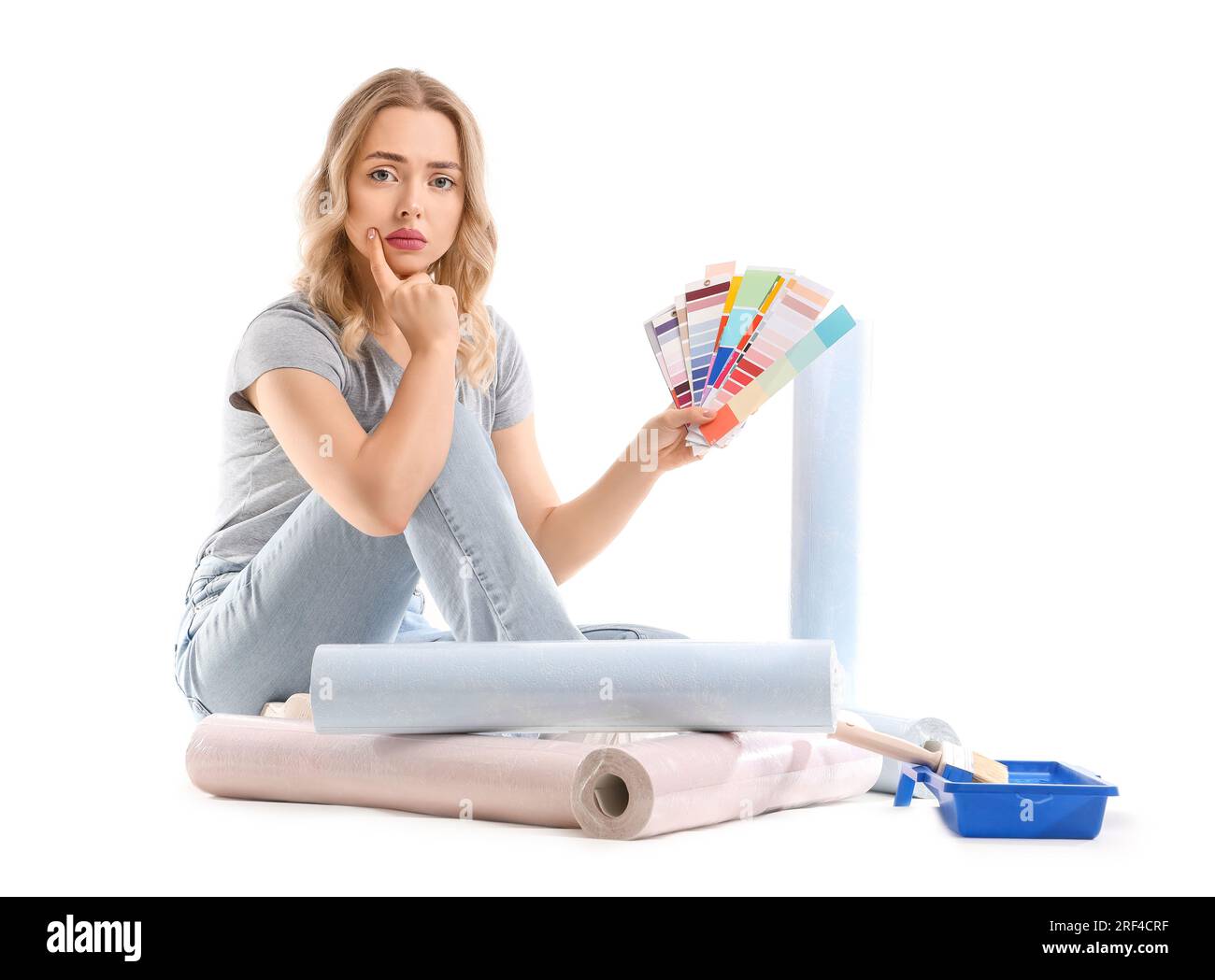 Upset young woman with color palettes and wallpaper rolls sitting on ...