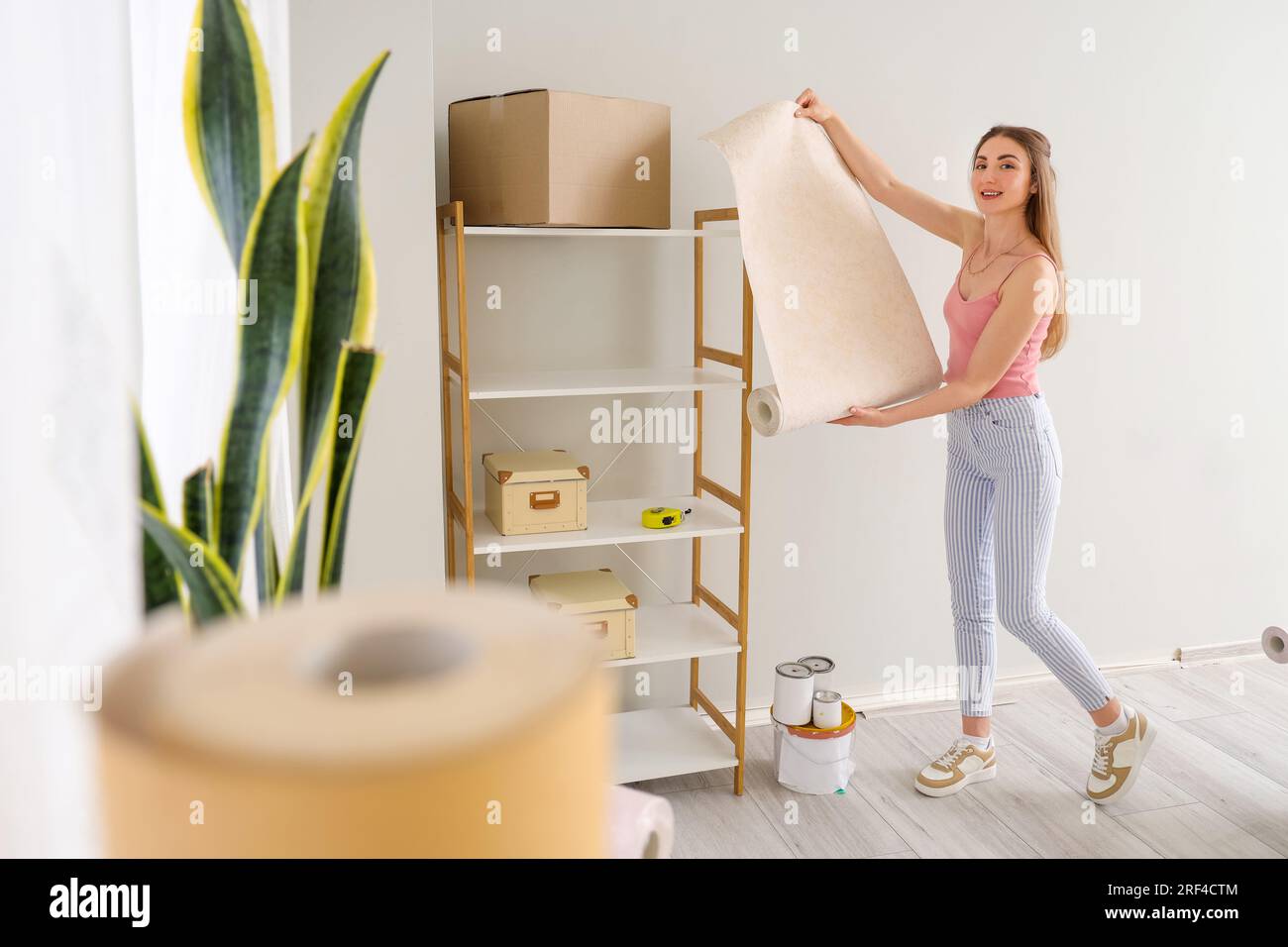Young woman with wallpaper roll at home Stock Photo - Alamy