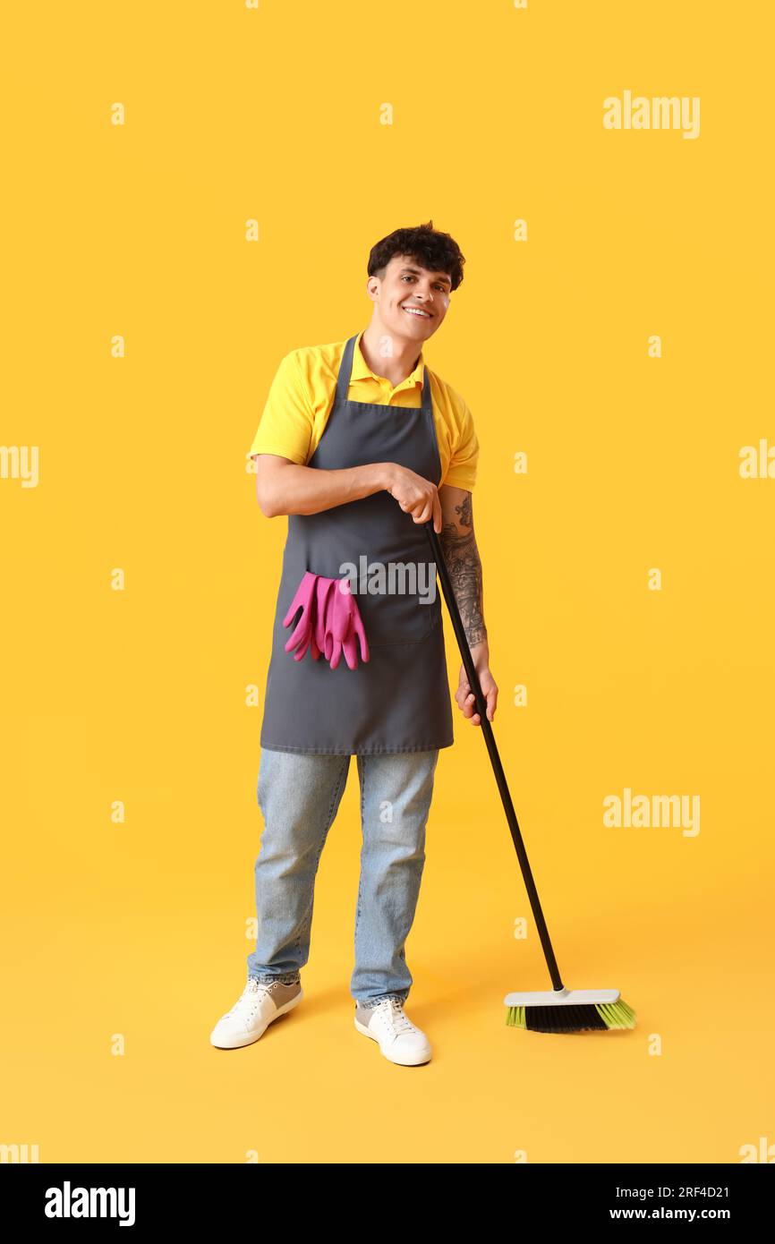 Male janitor with broom on yellow background Stock Photo - Alamy