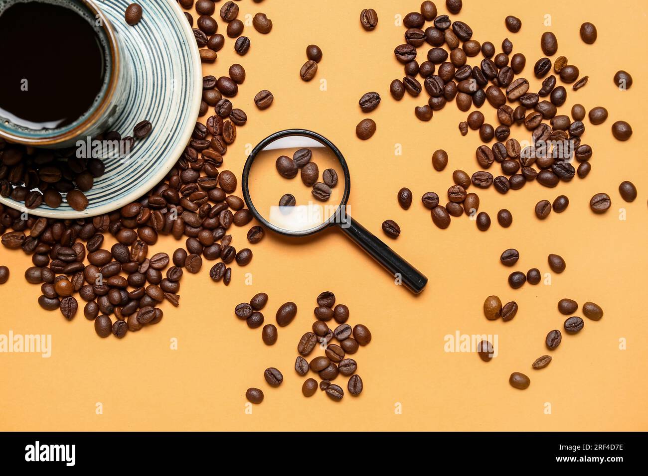 Magnifier and cup of coffee with beans on pale orange background Stock ...