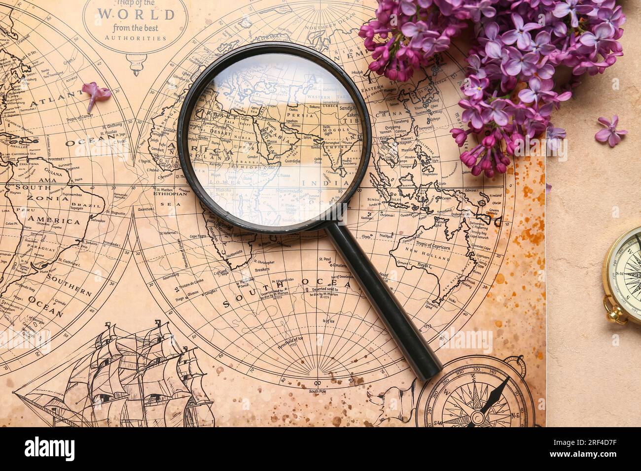 World map with compass, magnifier and lilac flowers on beige grunge ...