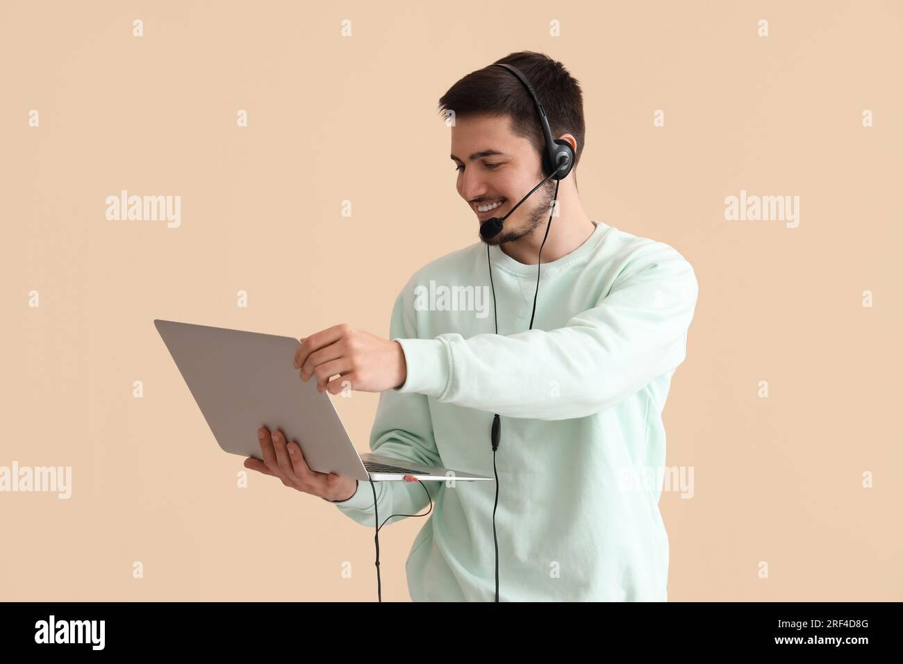 Male technical support agent with laptop on beige background Stock ...