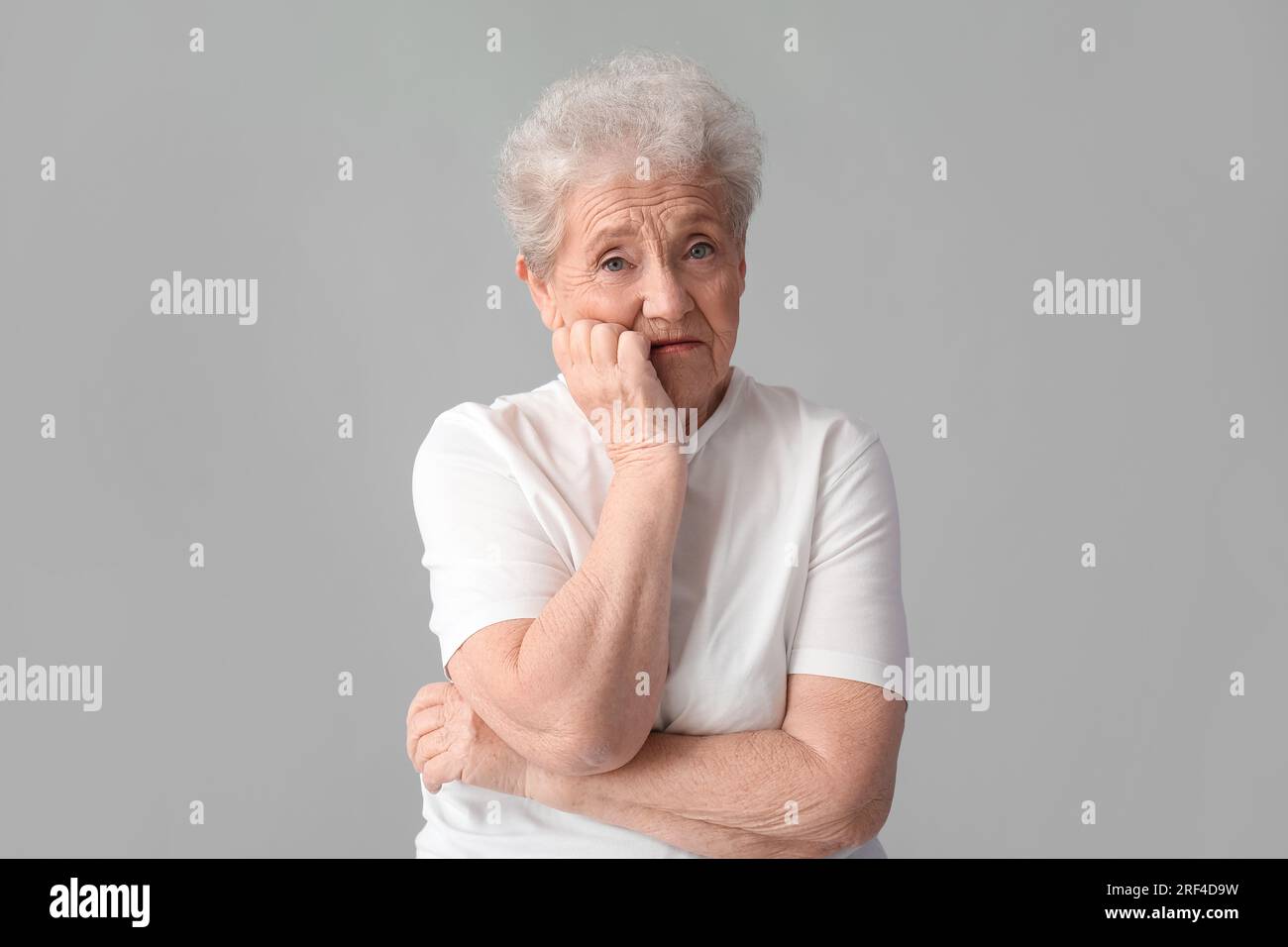 Upset senior woman on grey background Stock Photo - Alamy