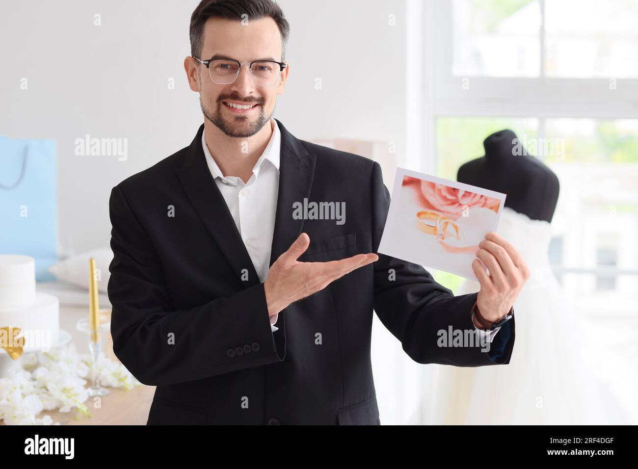 Male wedding planner with picture of rings in office Stock Photo - Alamy