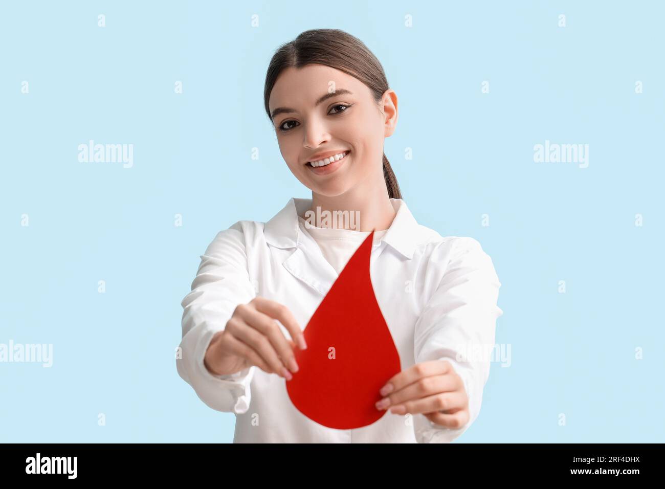Female doctor with paper blood drop on blue background Stock Photo - Alamy