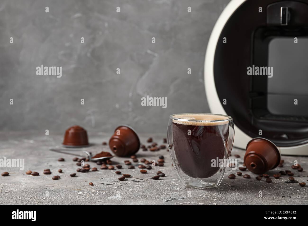 Glass of delicious espresso, capsule coffee maker, pods and beans on ...