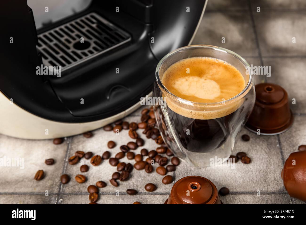 Glass of delicious espresso, capsule coffee maker, pods and beans on ...