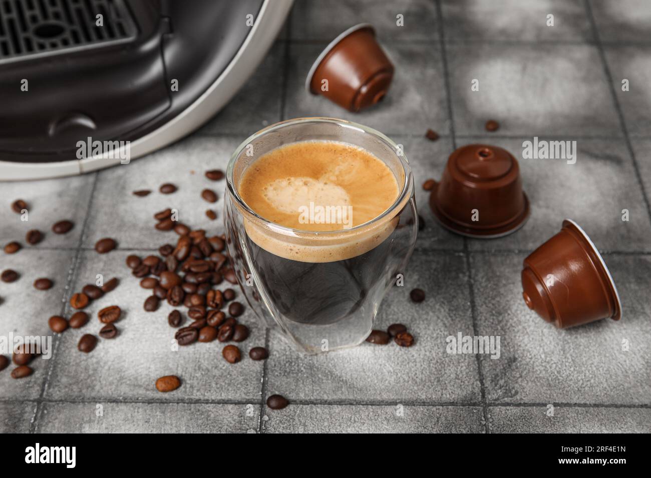 Glass of delicious espresso, pods and beans on grey grunge table Stock ...