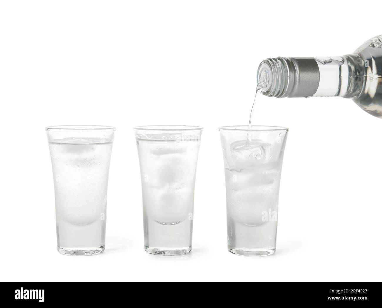 Pouring of vodka from bottle into glasses on white background Stock ...