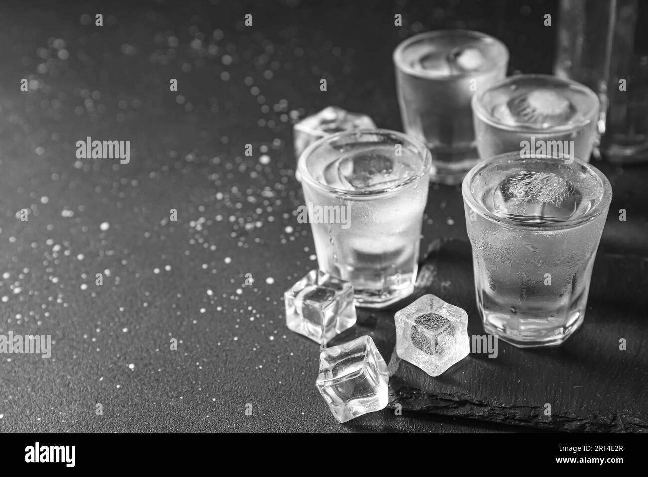 Shots of vodka with ice cubes on black background Stock Photo - Alamy