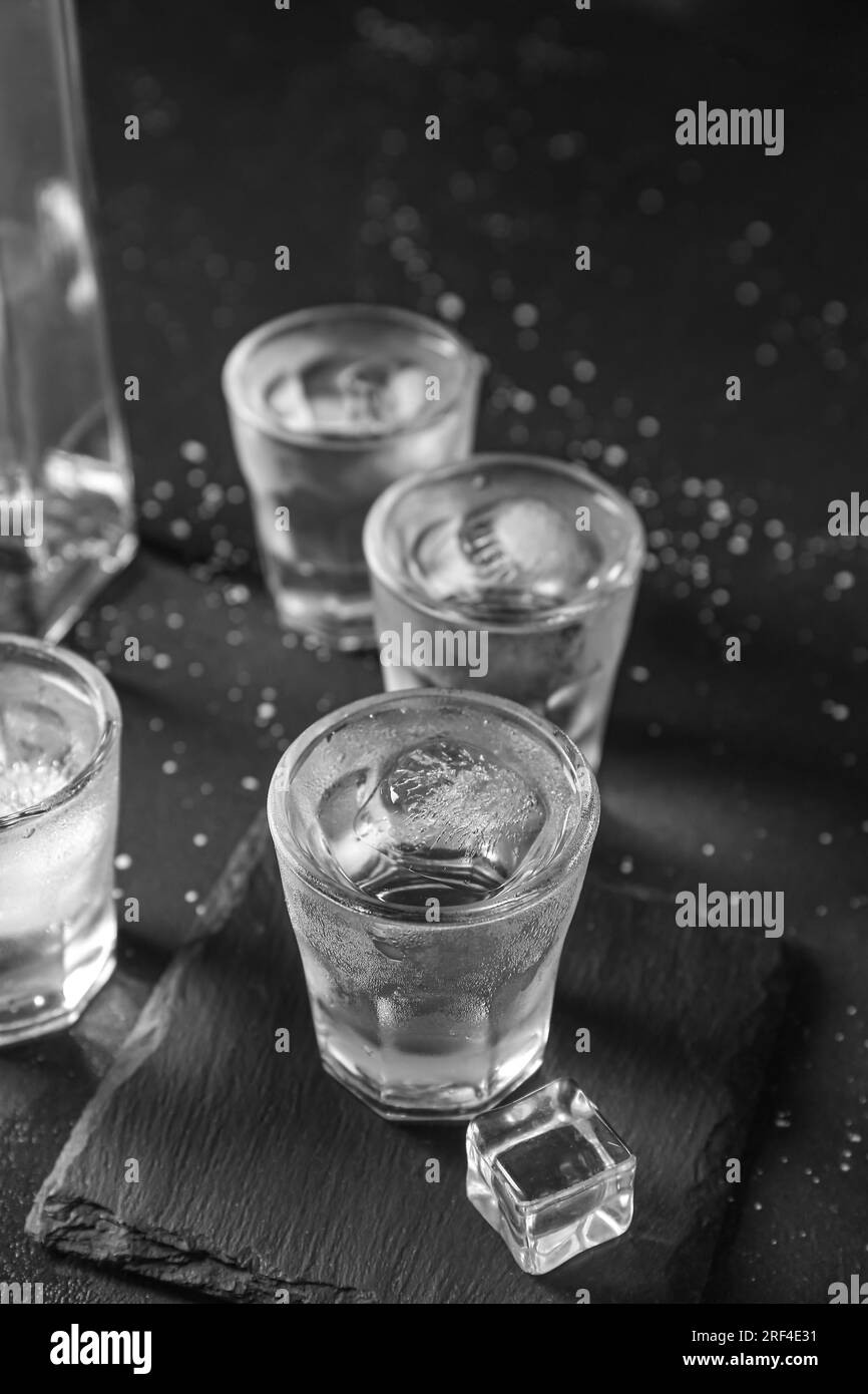 Shots of vodka with ice cubes on black background Stock Photo - Alamy