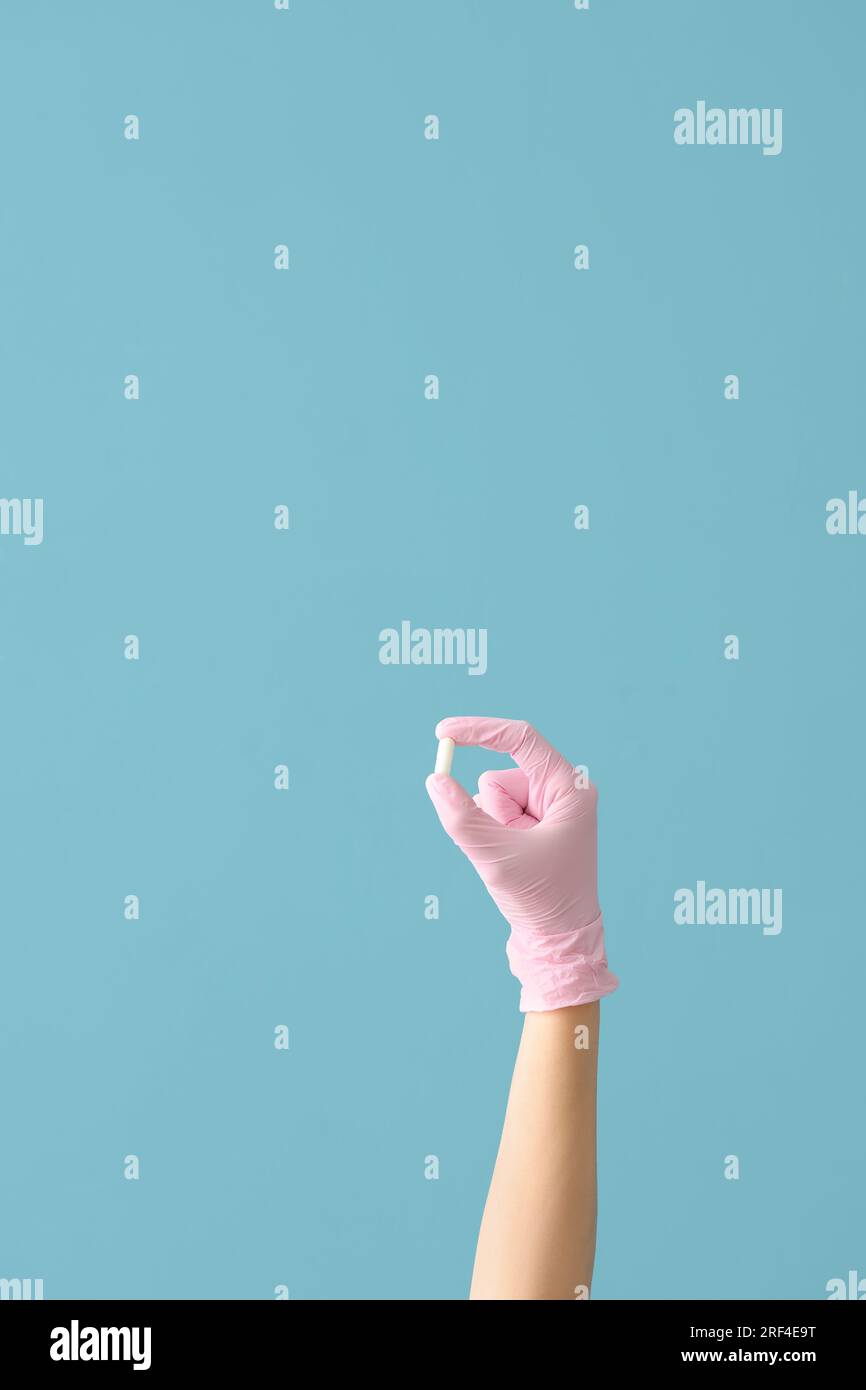 Female doctor's hand in glove with capsule on blue background Stock ...
