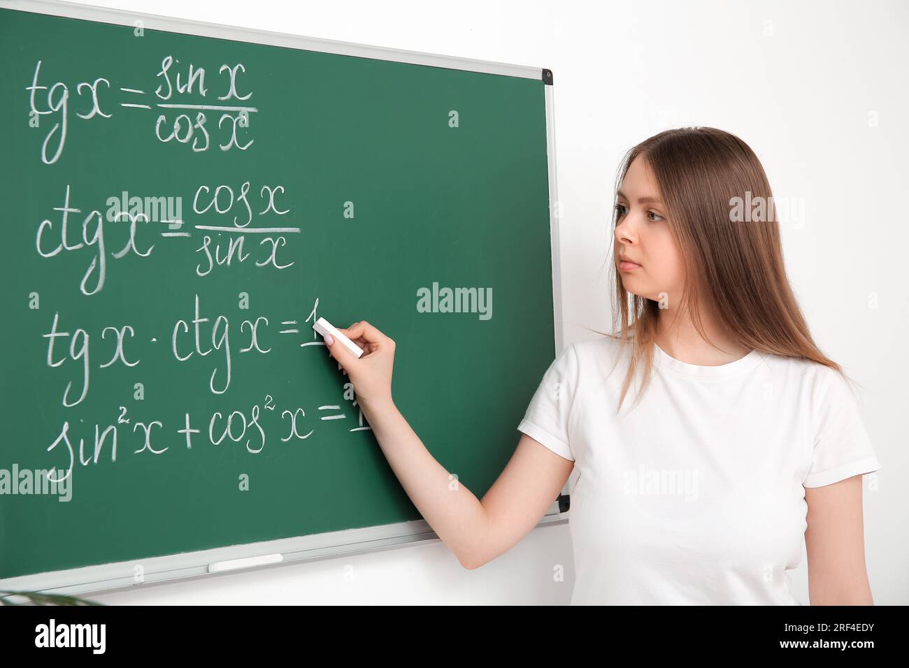 Young math teacher writing on blackboard in classroom Stock Photo - Alamy