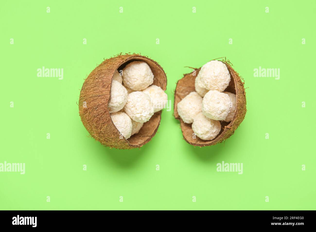 Coconut shells with white chocolate candies on green background Stock ...