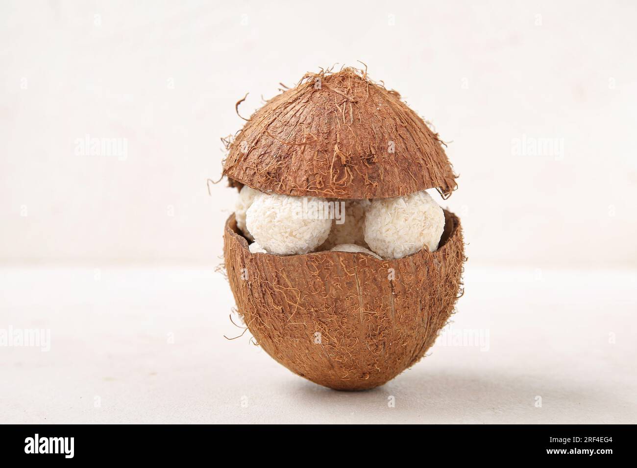 Coconut shell with white chocolate candies on light table Stock Photo ...