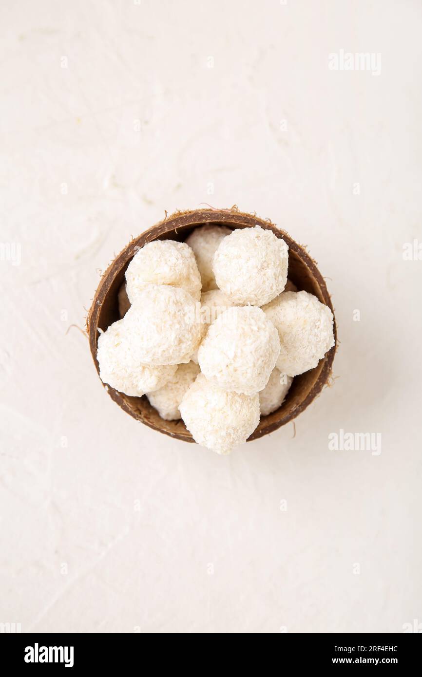 Coconut shell with white chocolate candies on light table Stock Photo ...