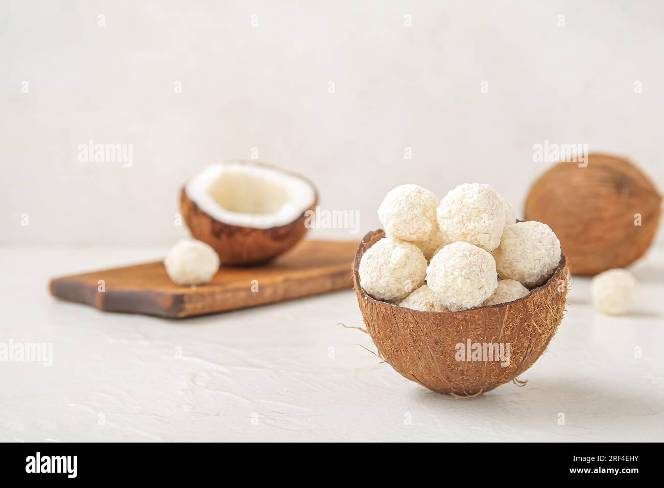 Coconut shell with white chocolate candies on light table Stock Photo ...