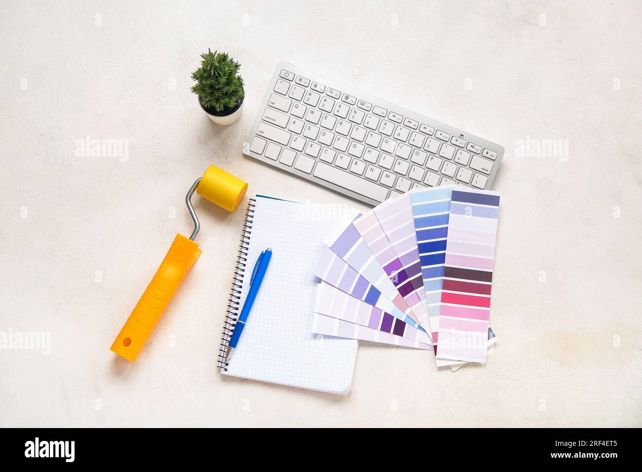 Many color palettes, PC keyboard, paint roller and notebook on light ...