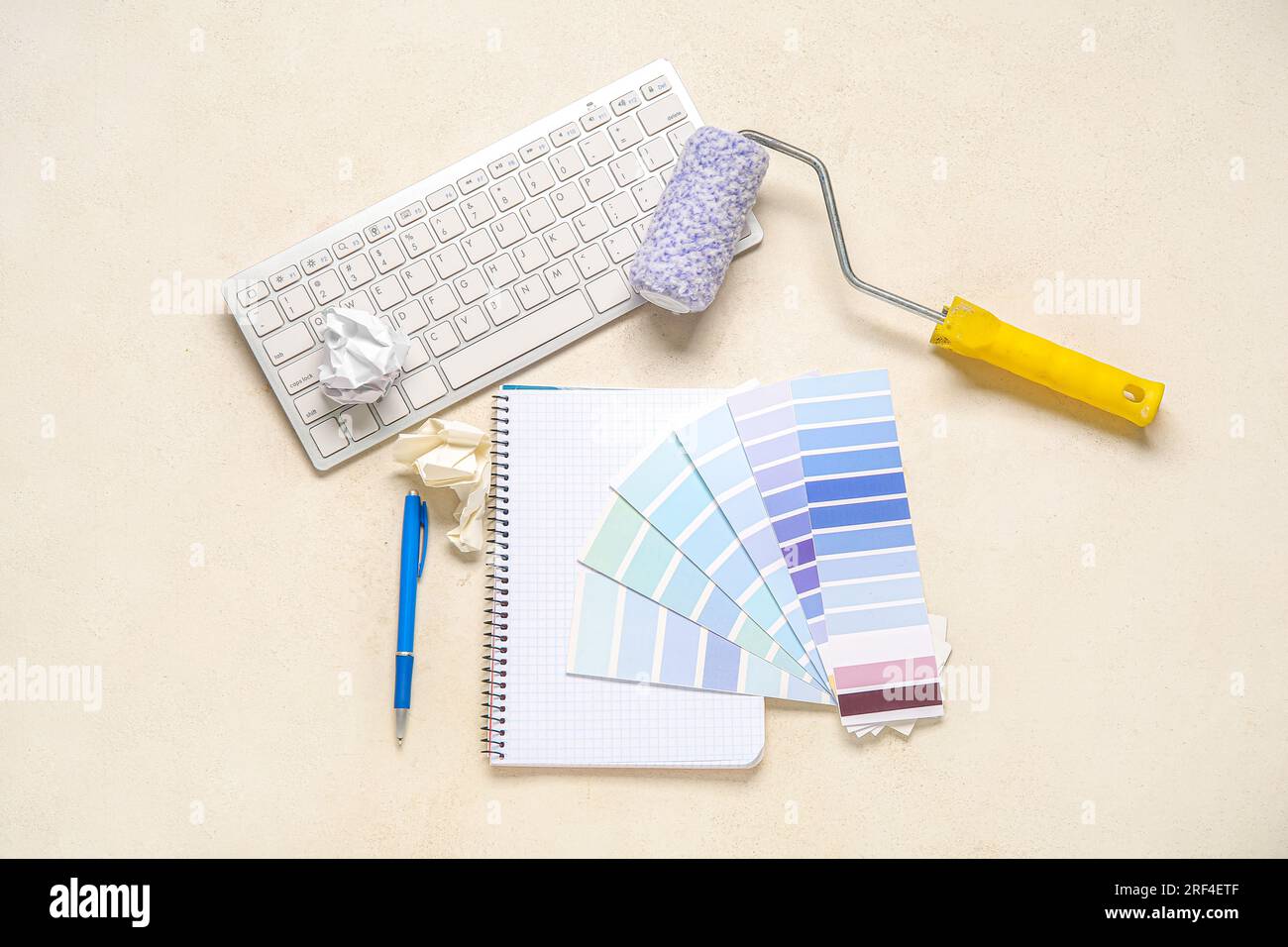 Color palettes, PC keyboard, paint roller and notebook on light ...