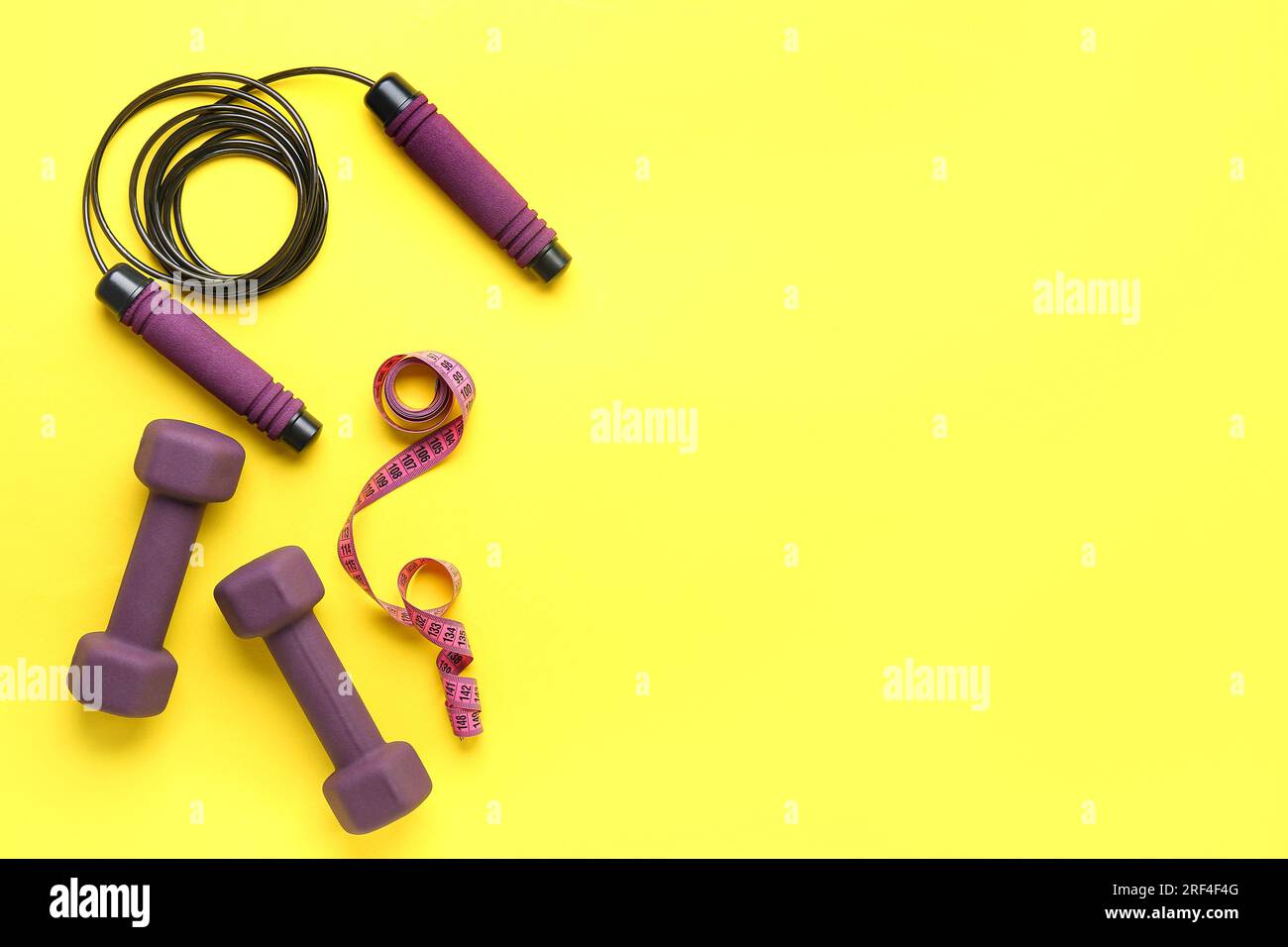 Skipping rope, dumbbells and measuring tape on yellow background Stock ...