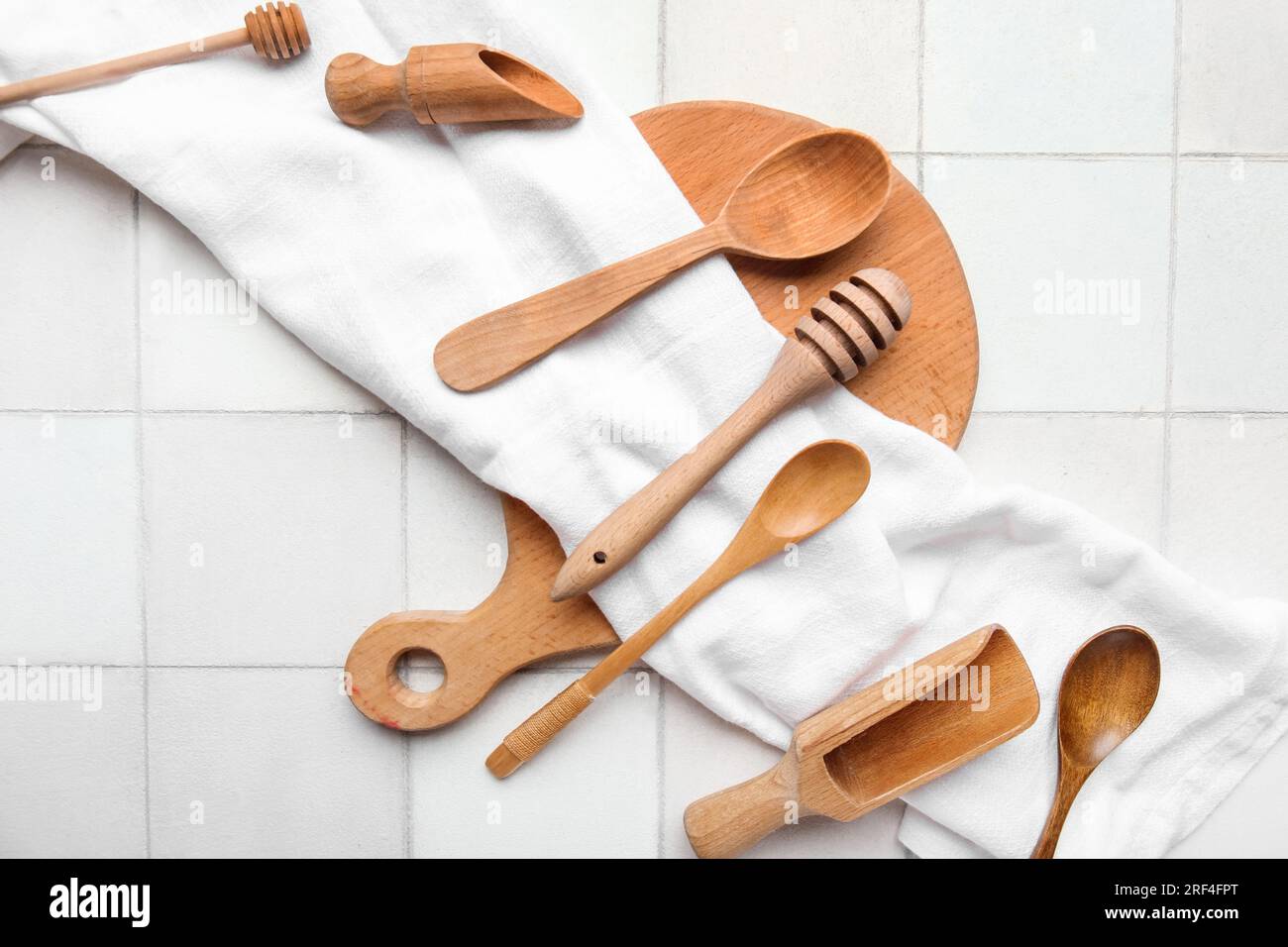 Composition with wooden kitchen utensils and napkin on light tile ...