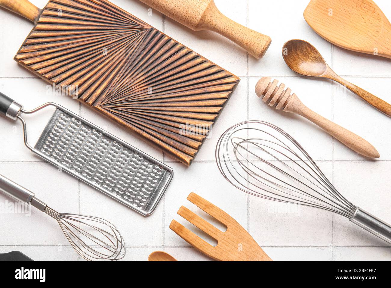 Composition with different kitchen utensils on light tile background ...